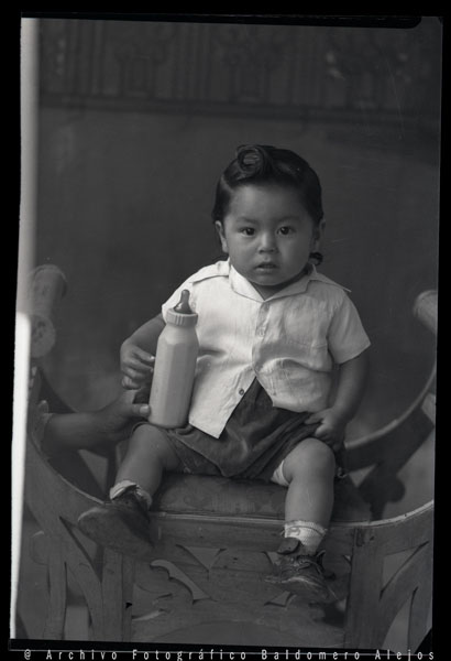 Bebé con rulos y biberón. · Catálogo Archivo Fotográfico Baldomero Alejos